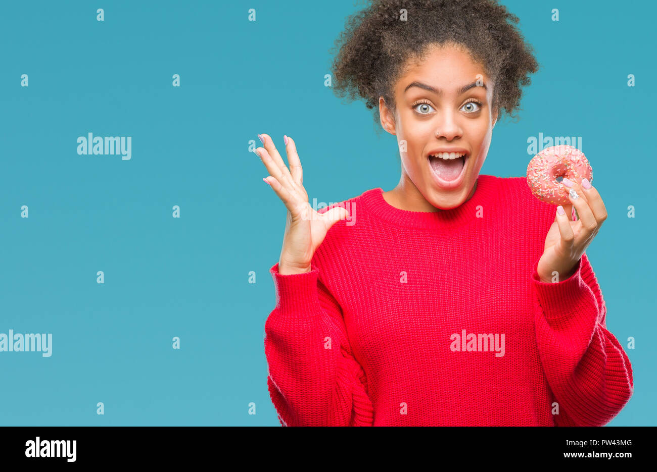 Young afro american woman eating donut over isolated background very ...