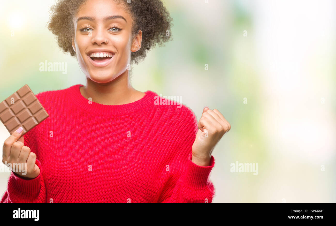 Young afro american woman eating chocolate bar over isolated background ...