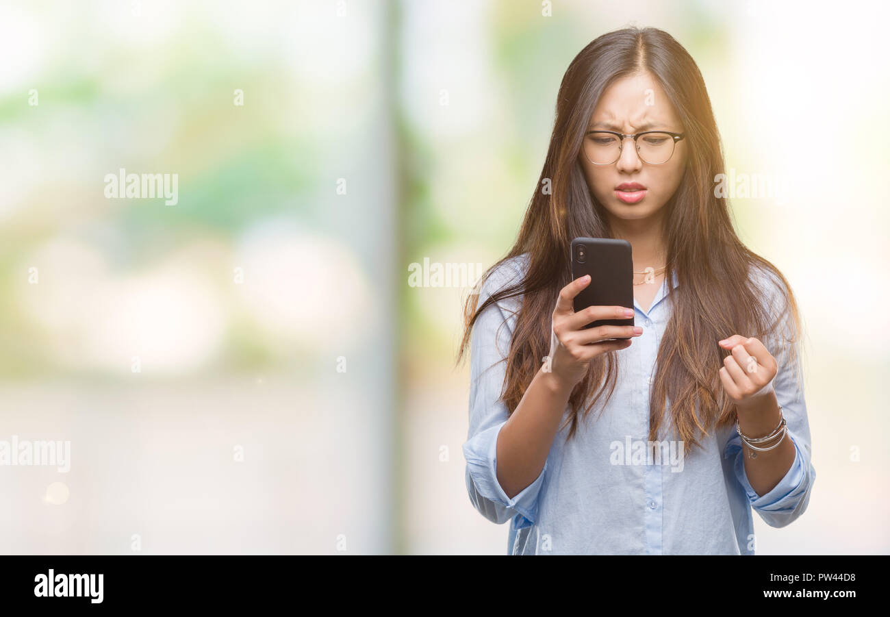 Young asian woman texting using smartphone over isolated background ...