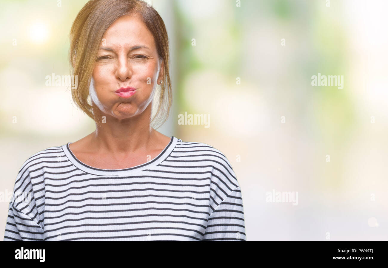 Middle age senior hispanic woman over isolated background puffing ...