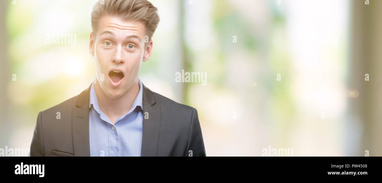 Young handsome blond business man scared in shock with a surprise face ...