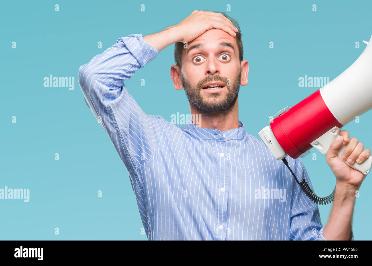 Young handsome man yelling through megaphone over isolated background ...