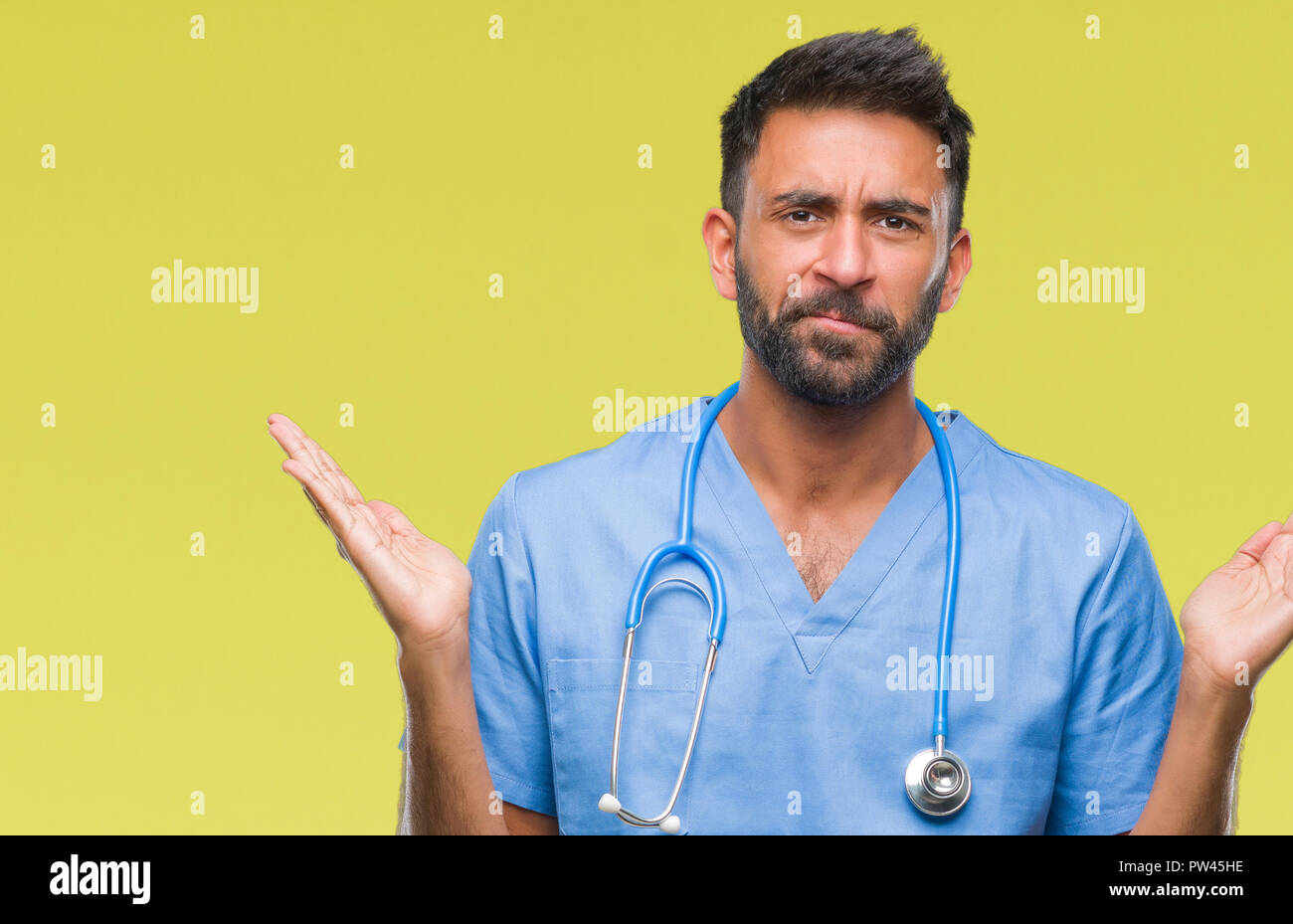 Adult hispanic doctor or surgeon man over isolated background clueless ...
