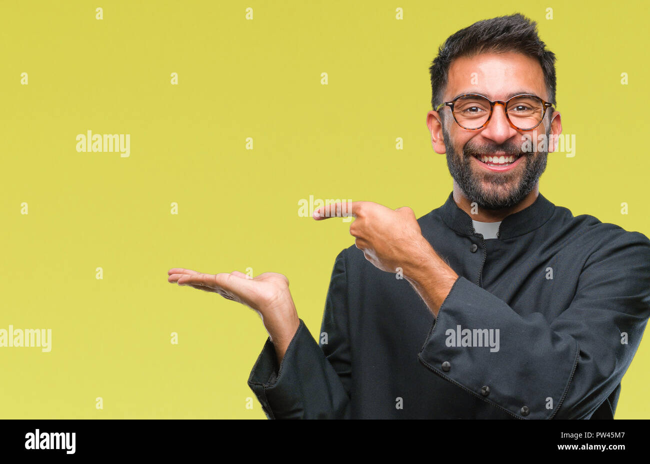 Adult hispanic catholic priest man over isolated background amazed and ...