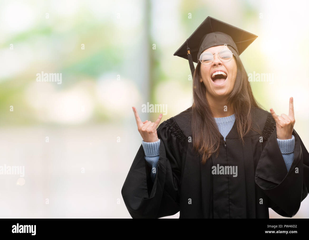 Young hispanic woman wearing graduated cap and uniform shouting with ...