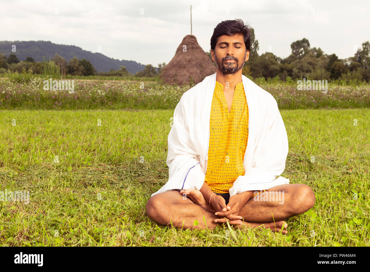 Indian yoga master practicing meditation in lotus postion joined hands ...
