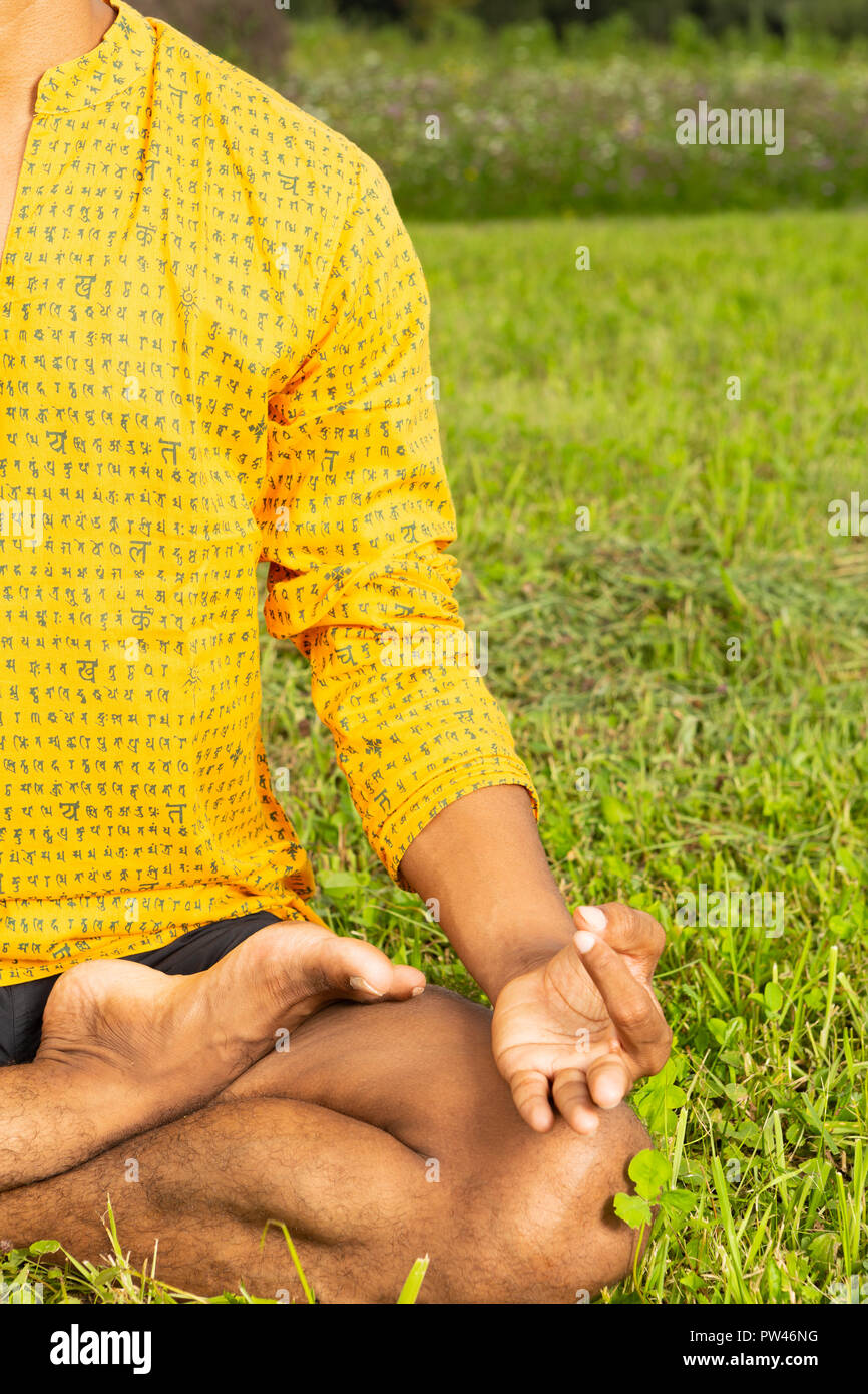 Half- view of lotus position body of indian yoga master wearing yellow ...