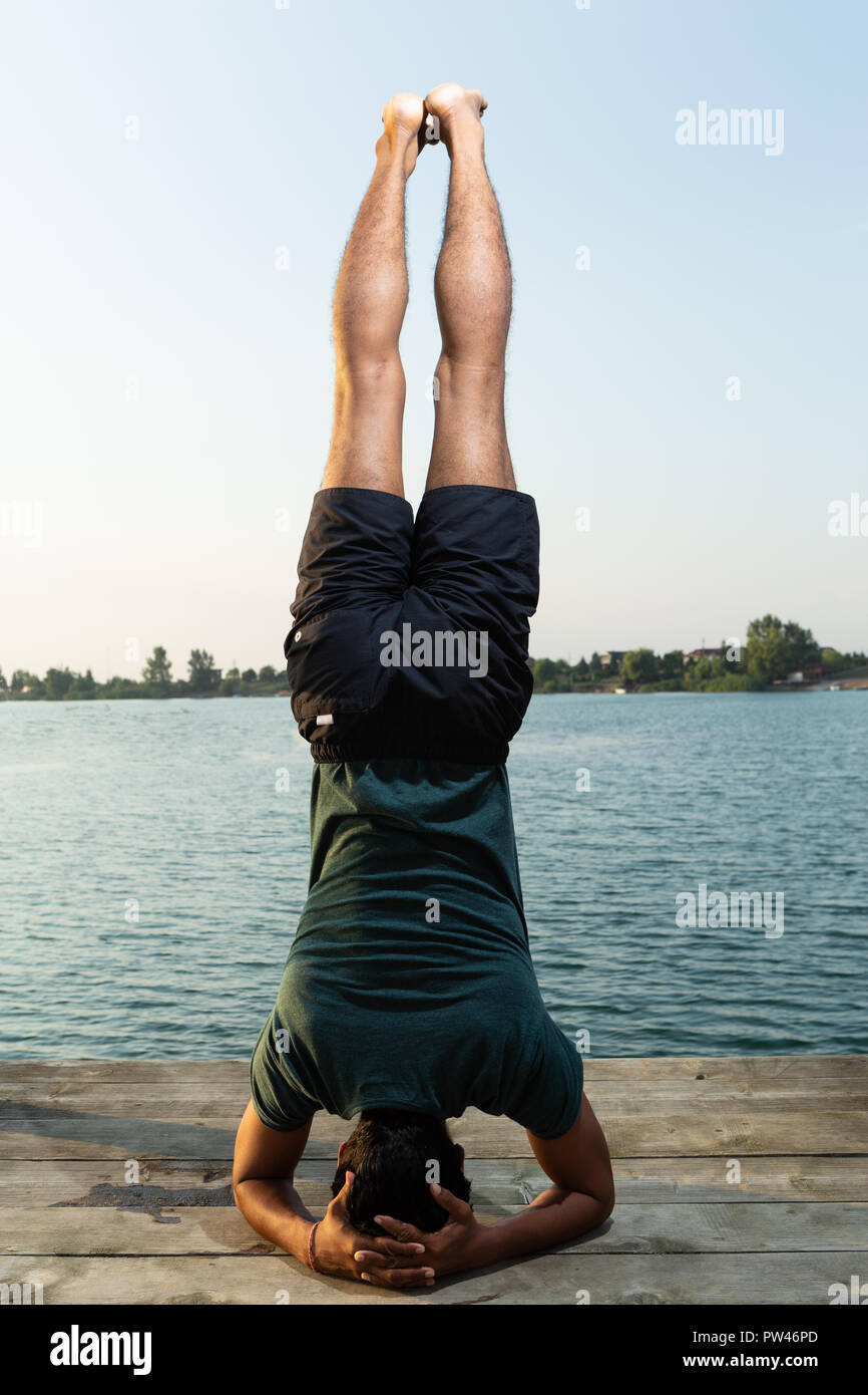 Inversion legs up pose near lake by indian yoga master with natural ...