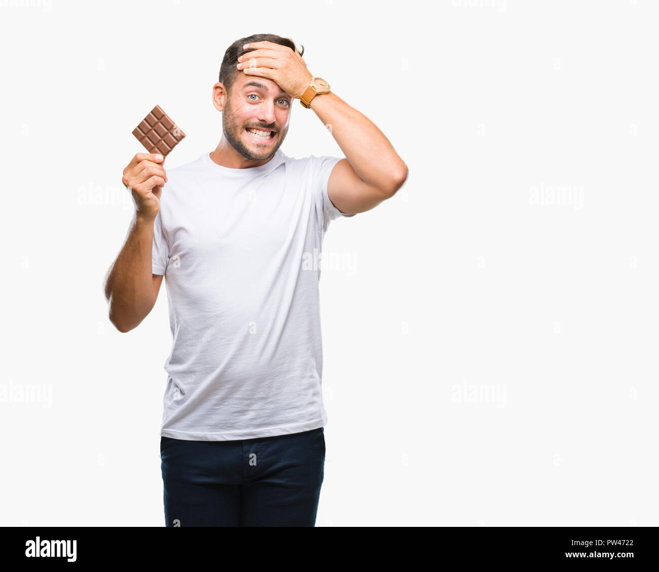 Young handsome man eating chocolate bar over isolated background ...