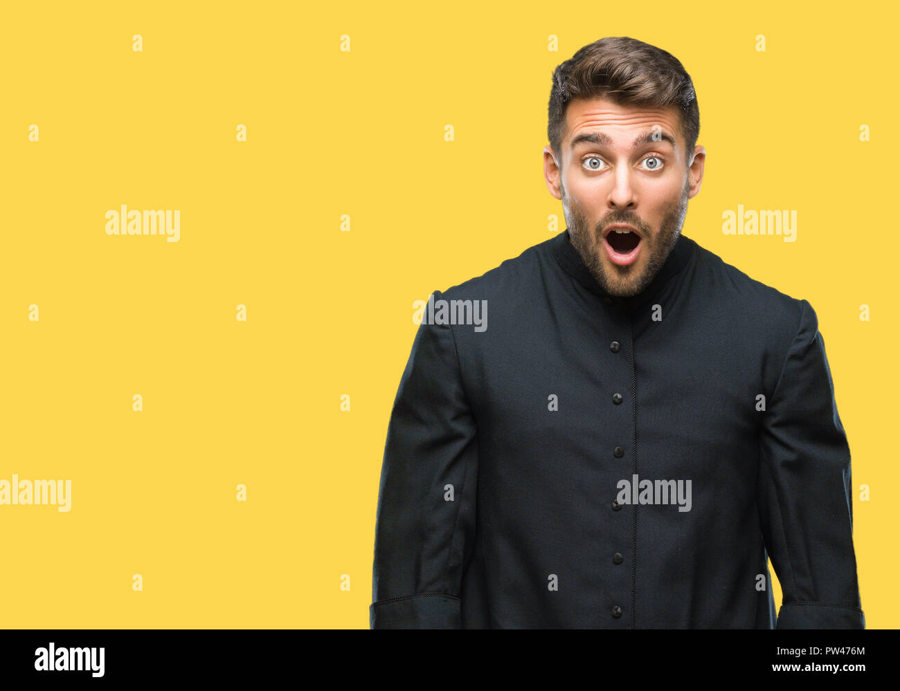 Young catholic christian priest man over isolated background afraid and ...