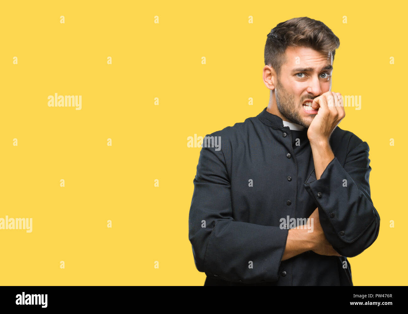 Young catholic christian priest man over isolated background looking ...