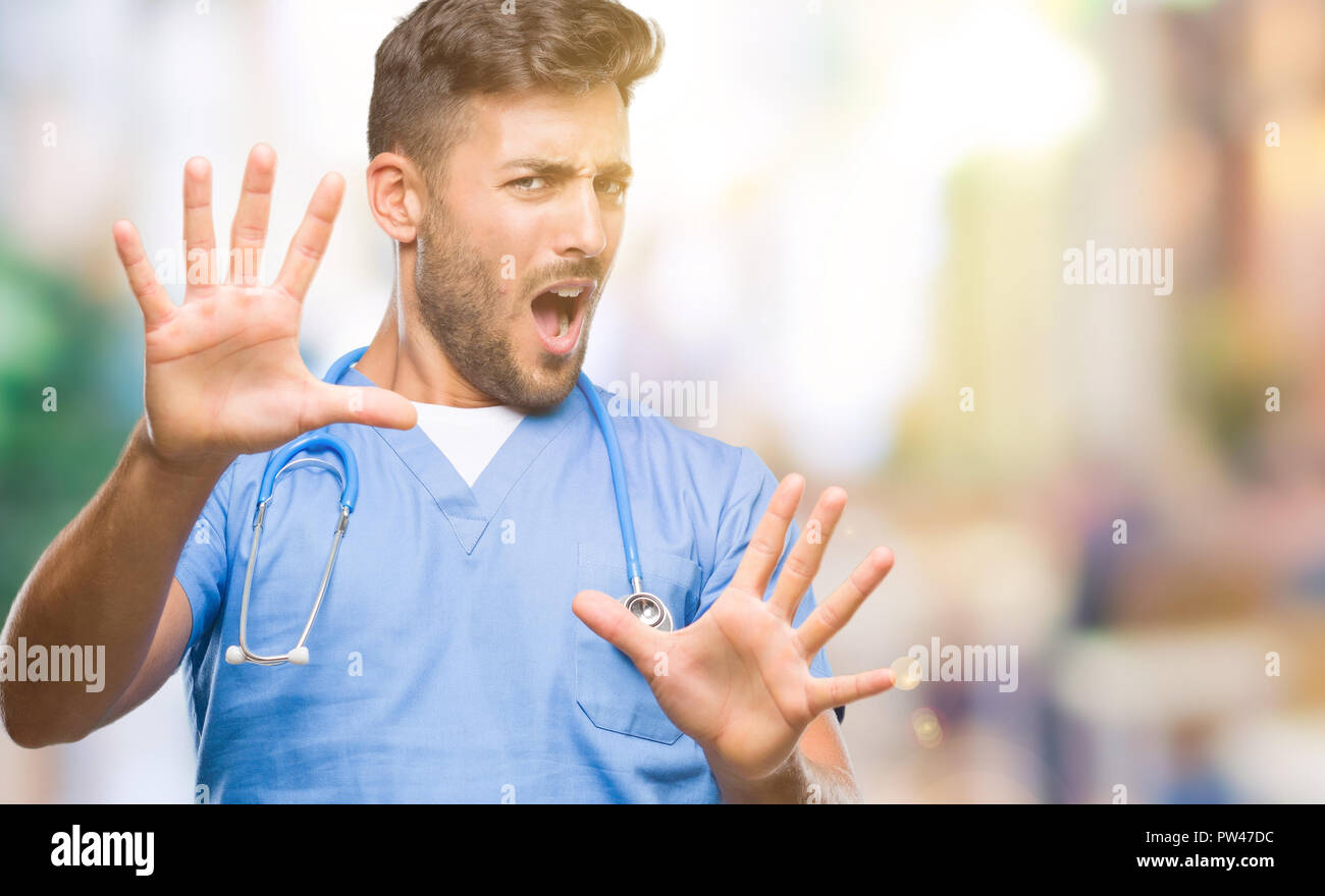 Young handsome doctor surgeon man over isolated background afraid and ...