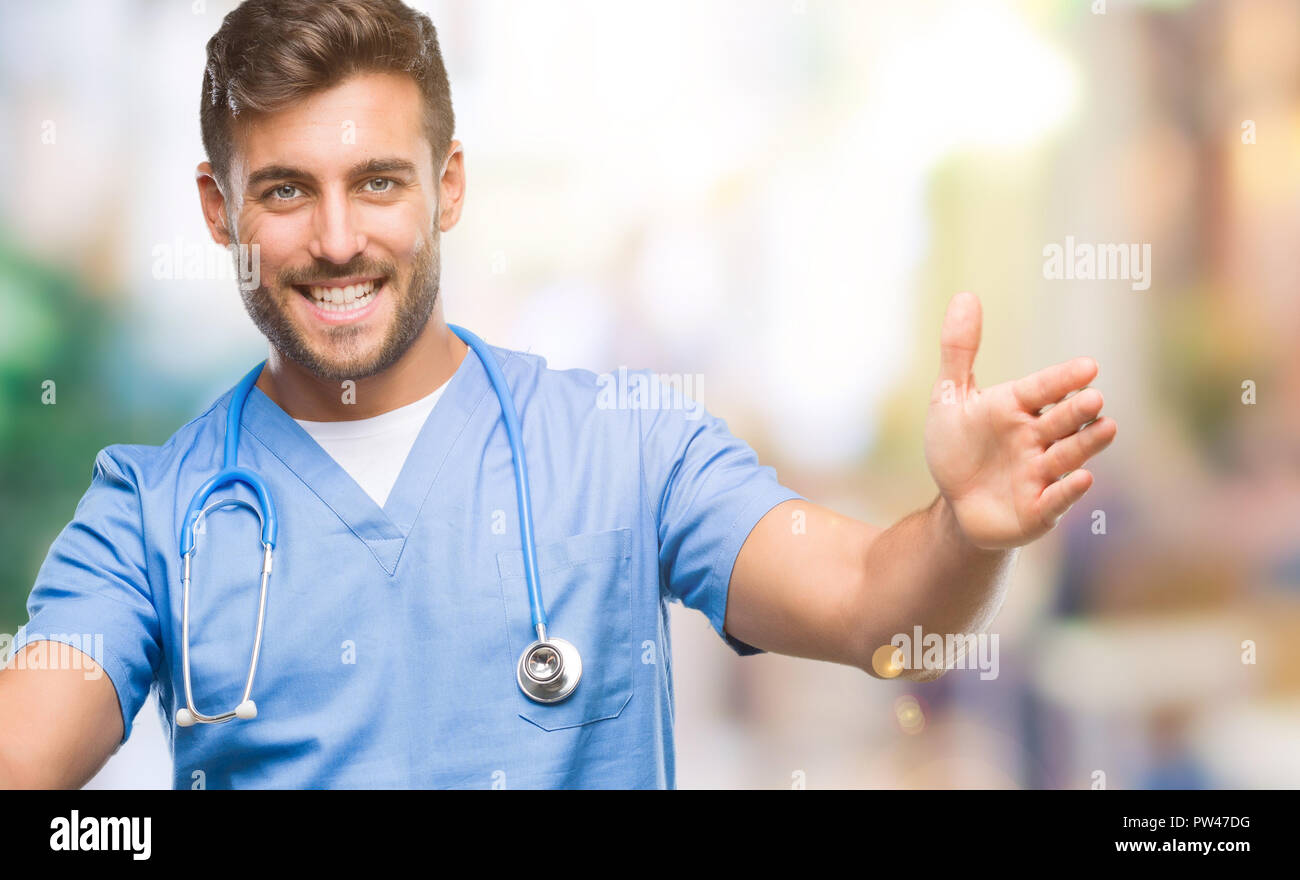 Young handsome doctor surgeon man over isolated background looking at ...