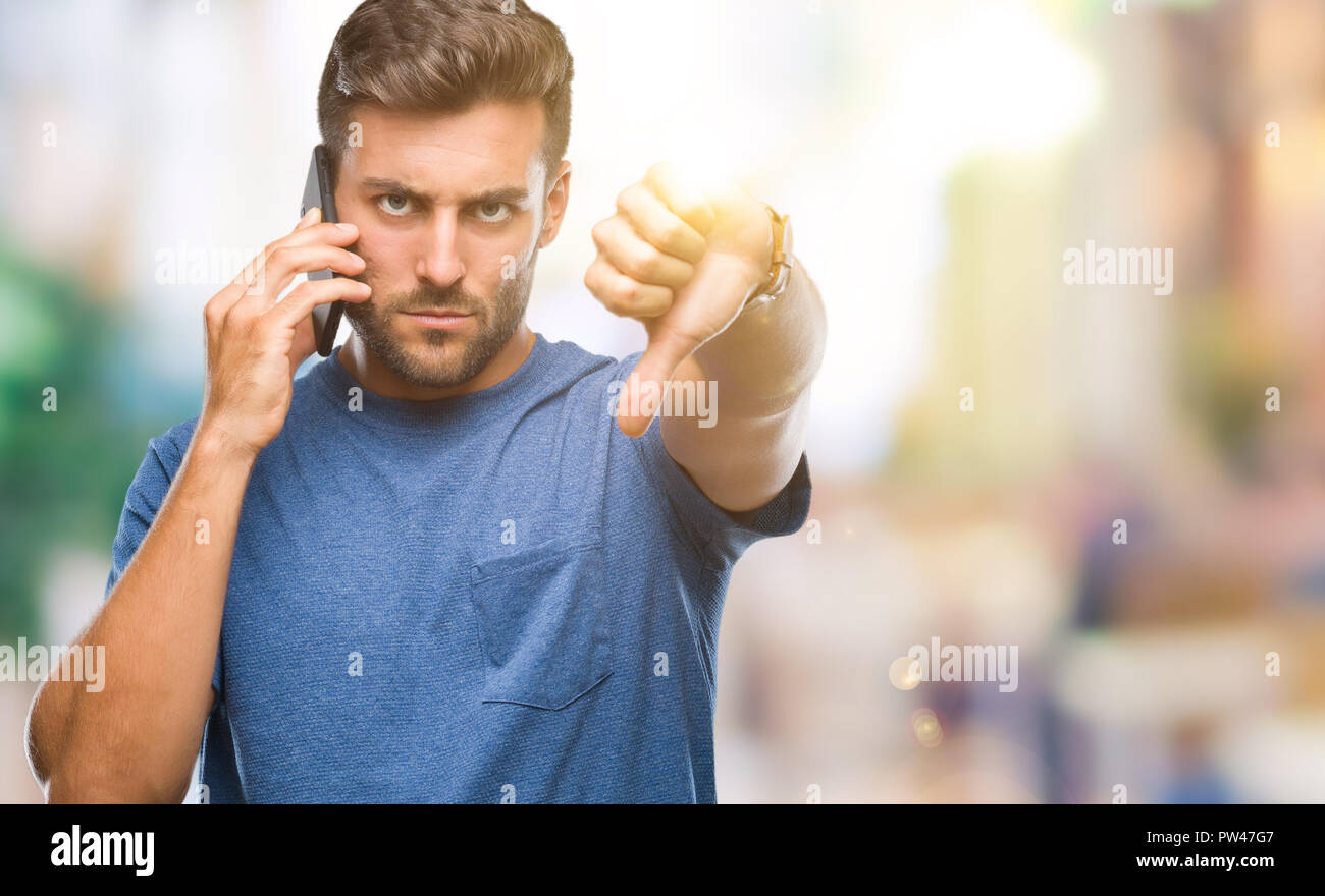 Young handsome man talking on smartphone over isolated background with ...