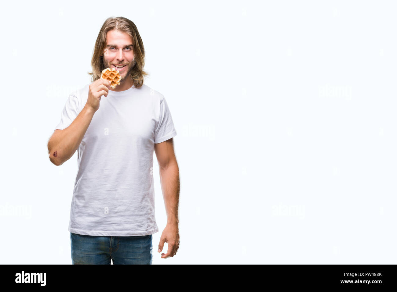 Young handsome man with long hair over isolated background eating ...