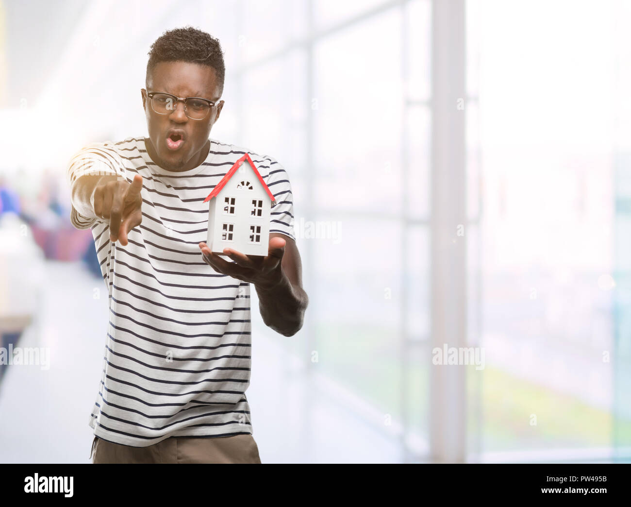 Young african american man holding house pointing with finger to the ...