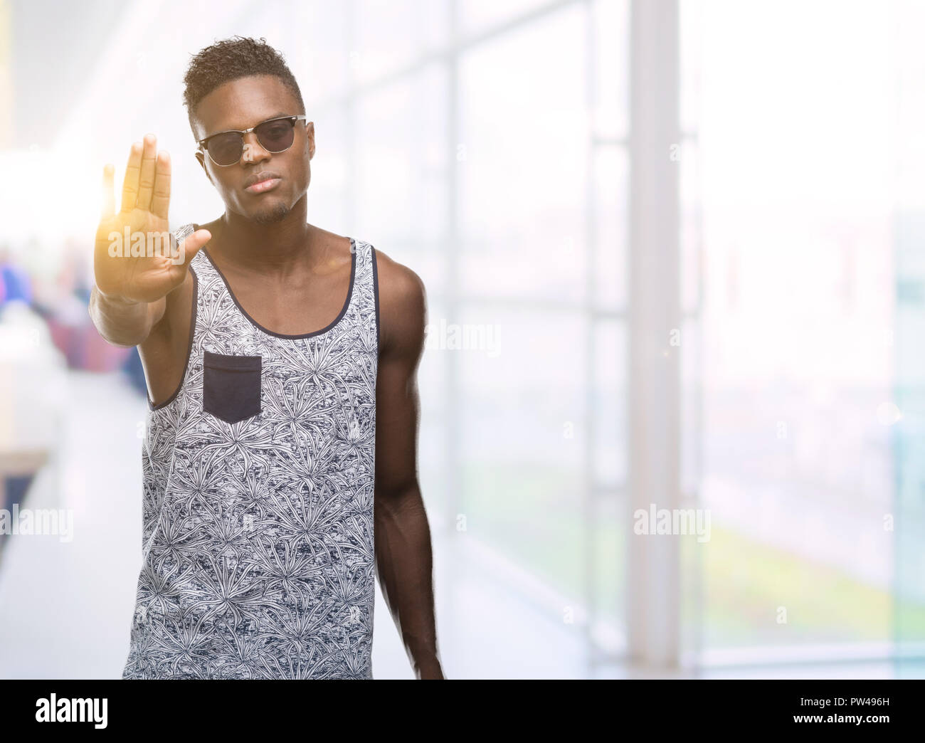 Young african american man with open hand doing stop sign with serious ...