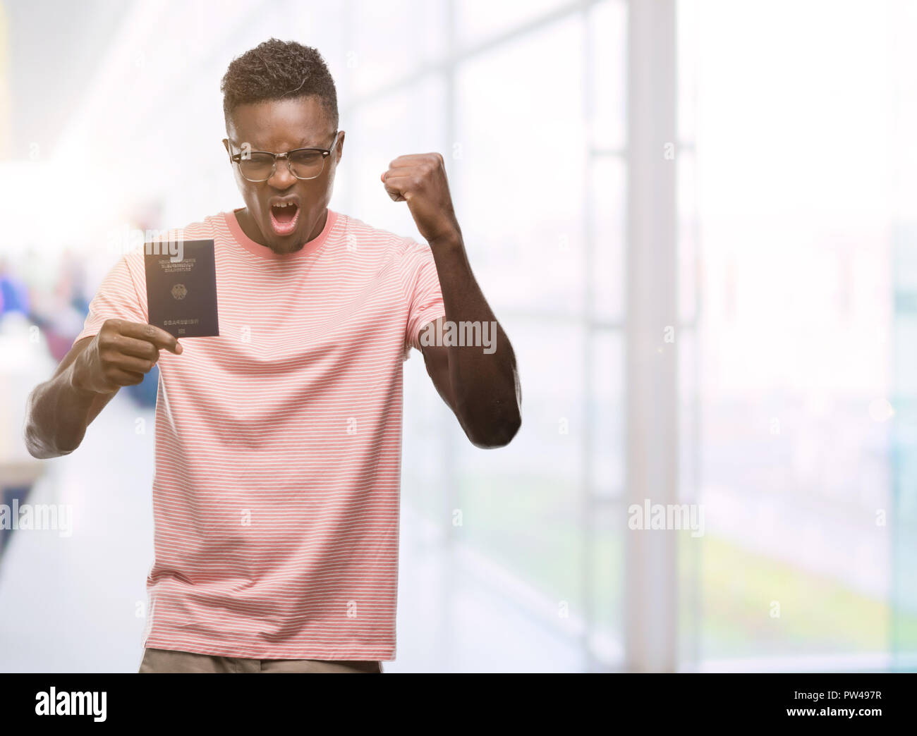 Young african american man holding german passport annoyed and ...