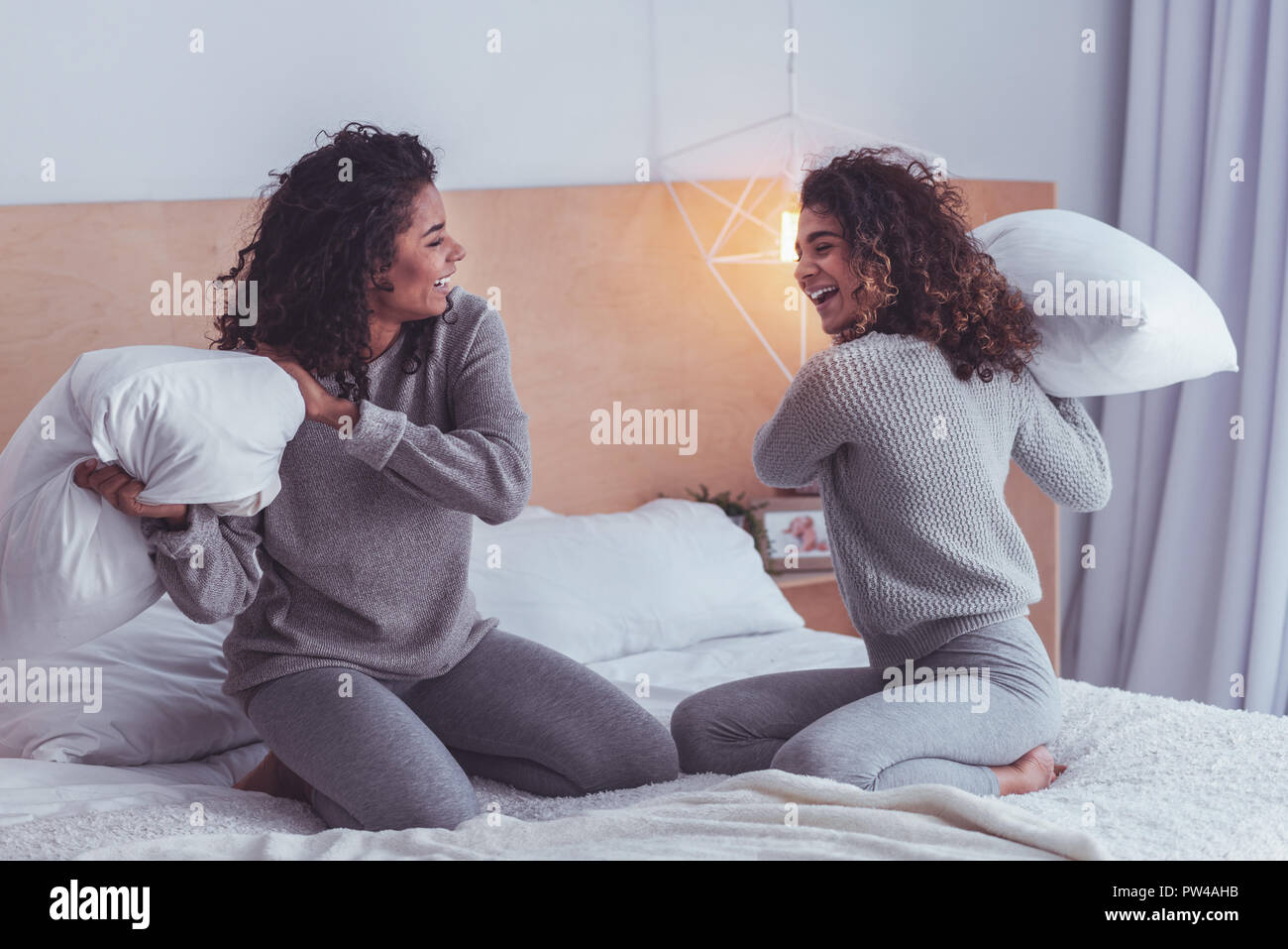 Two laughing friends enjoying pillow battle at home Stock Photo - Alamy