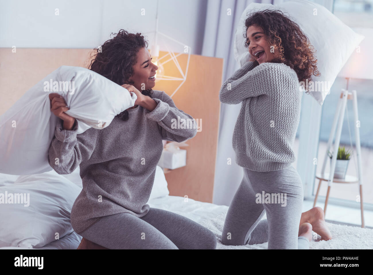 Happy siblings feeling cheerful while having pillow battle Stock Photo ...