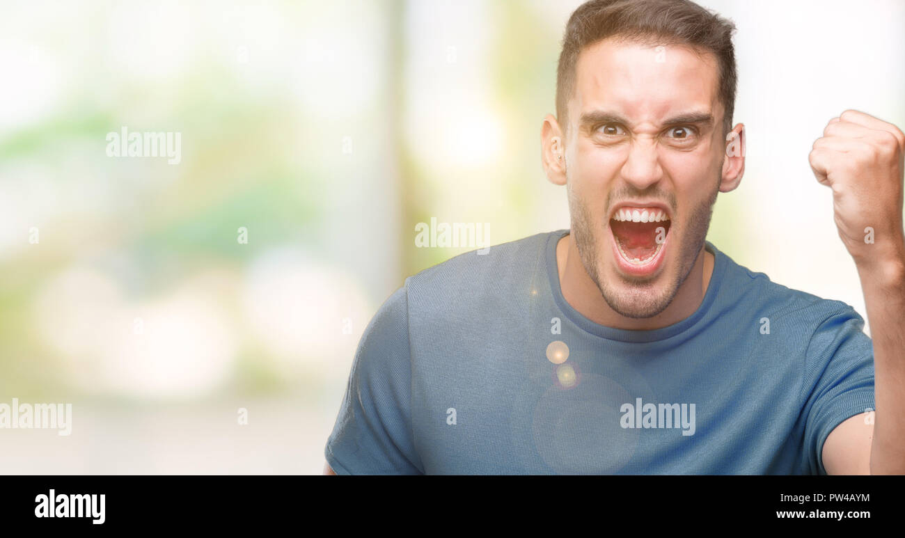 Handsome young casual man angry and mad raising fist frustrated and ...