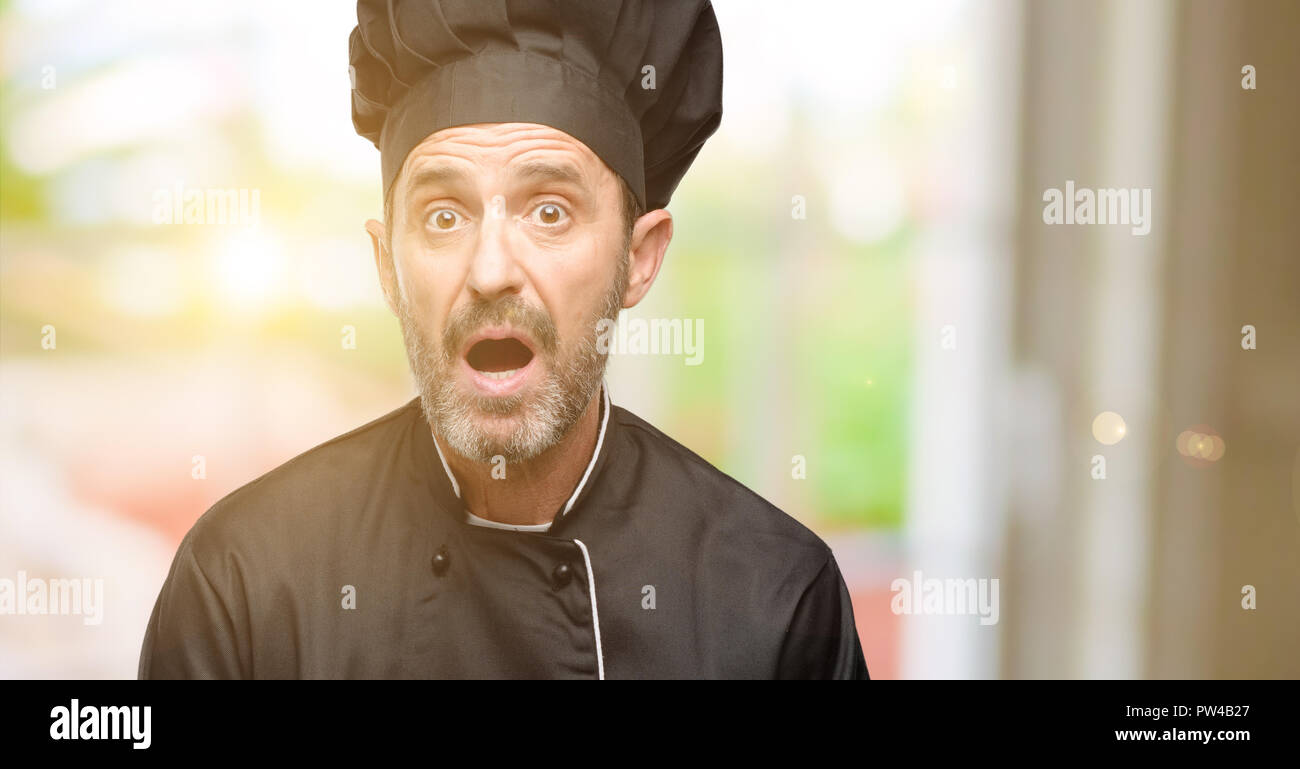 Senior cook man, wearing chef hat scared in shock, expressing panic and ...