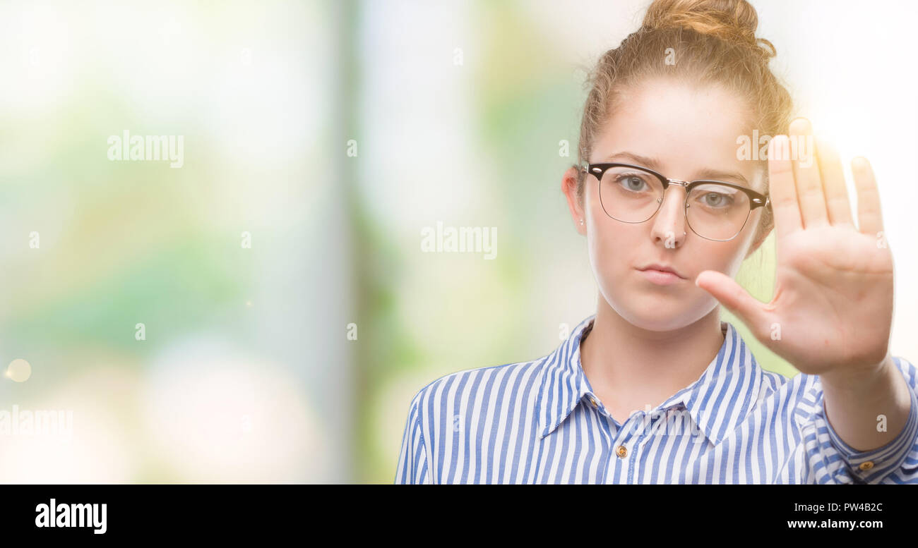 Young blonde business woman doing stop sing with palm of the hand ...