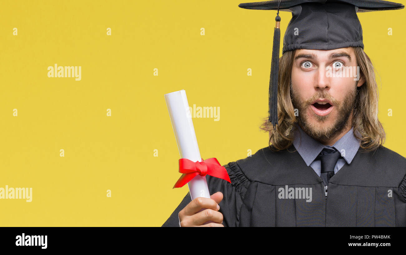 Young handsome graduate man with long hair holding degree over isolated ...