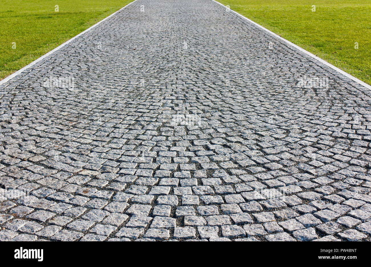 A cobbled pavement with green, vivid grass Stock Photo - Alamy