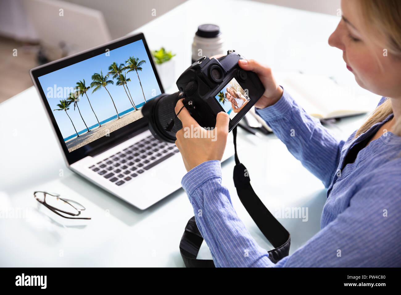 Female Editor Looking At Couple Photograph In DSLR Camera With Laptop ...
