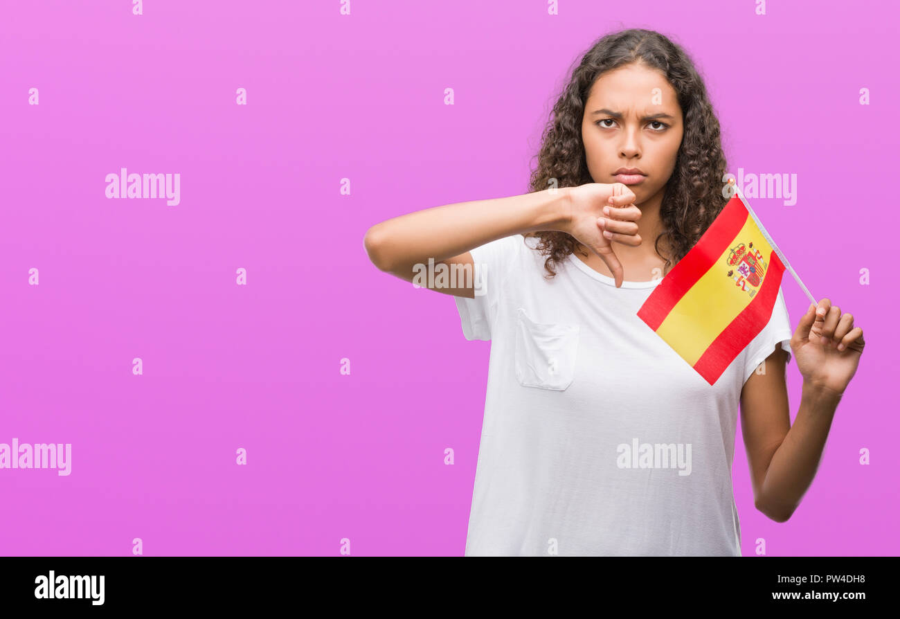 Young hispanic woman holding flag of Spain with angry face, negative ...
