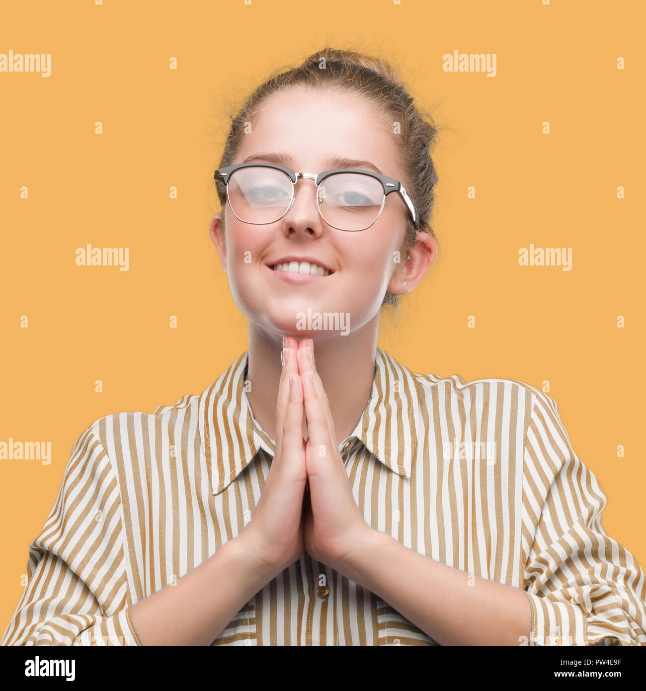 Young blonde business woman praying with hands together asking for ...