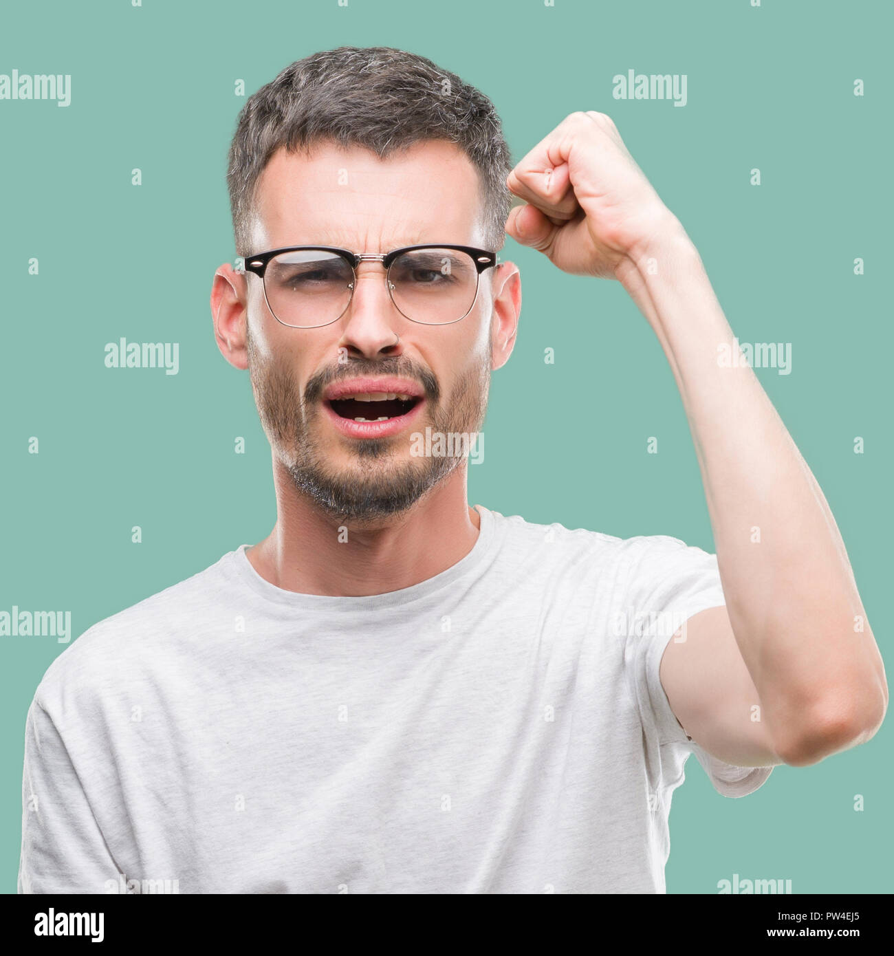 Young tattooed adult man angry and mad raising fist frustrated and ...