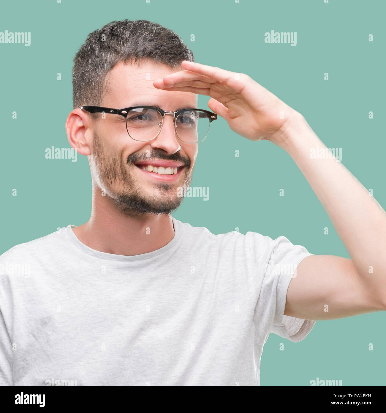 Young tattooed adult man very happy and smiling looking far away with ...