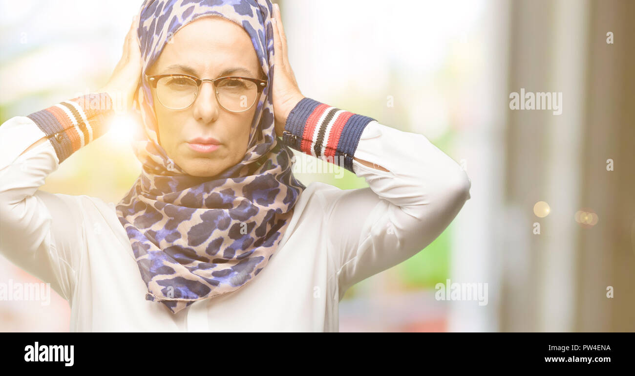 Middle age muslim arab woman wearing hijab covering ears ignoring ...