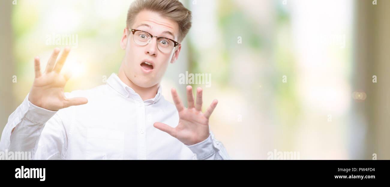 Young handsome blond man afraid and terrified with fear expression stop ...