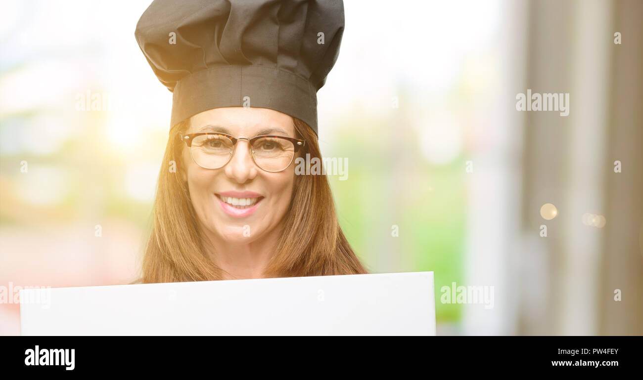 Middle age cook woman wearing chef apron holding blank advertising ...