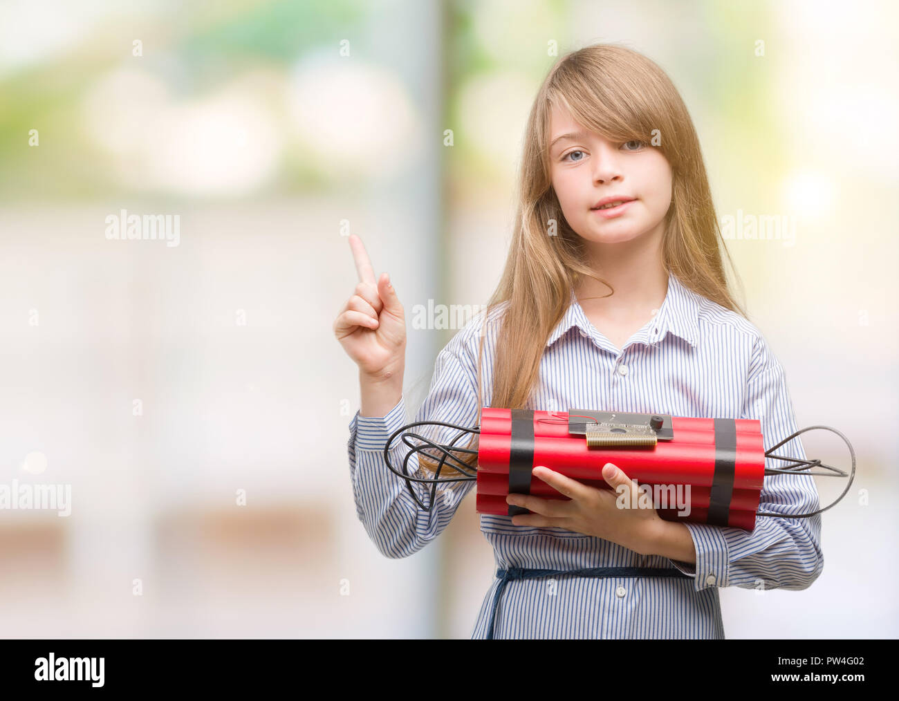 Young blonde child holding dynamite bomb very happy pointing with hand ...