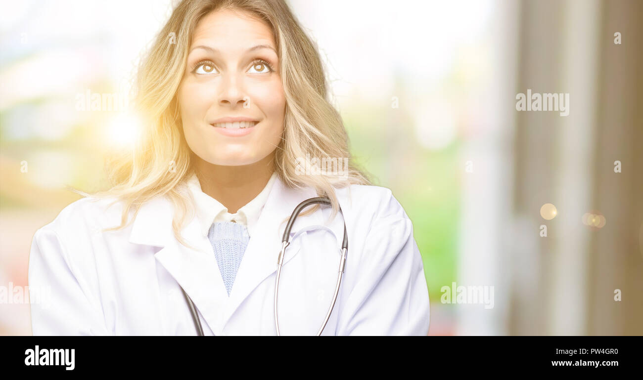 Young doctor woman, medical professional thinking and looking up ...