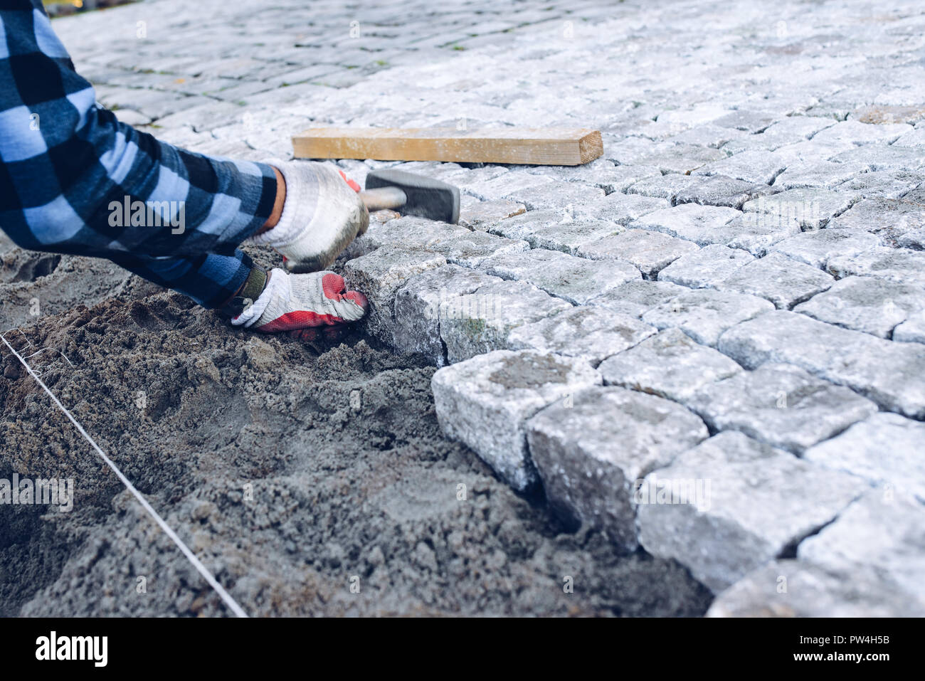 construction worker placing stone tiles for pavement, terrace. Worker ...