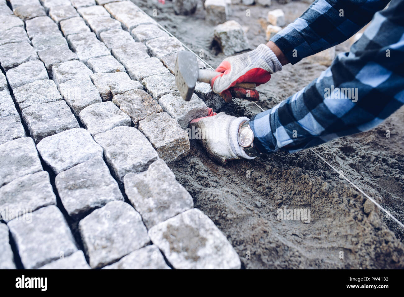 industrial worker installing pavement rocks, cobblestone blocks on road ...