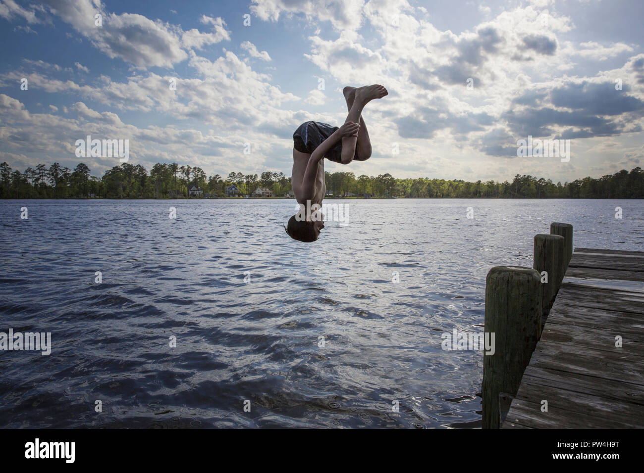 Shirtless boy jumping into lake against cloudy sky Stock Photo - Alamy