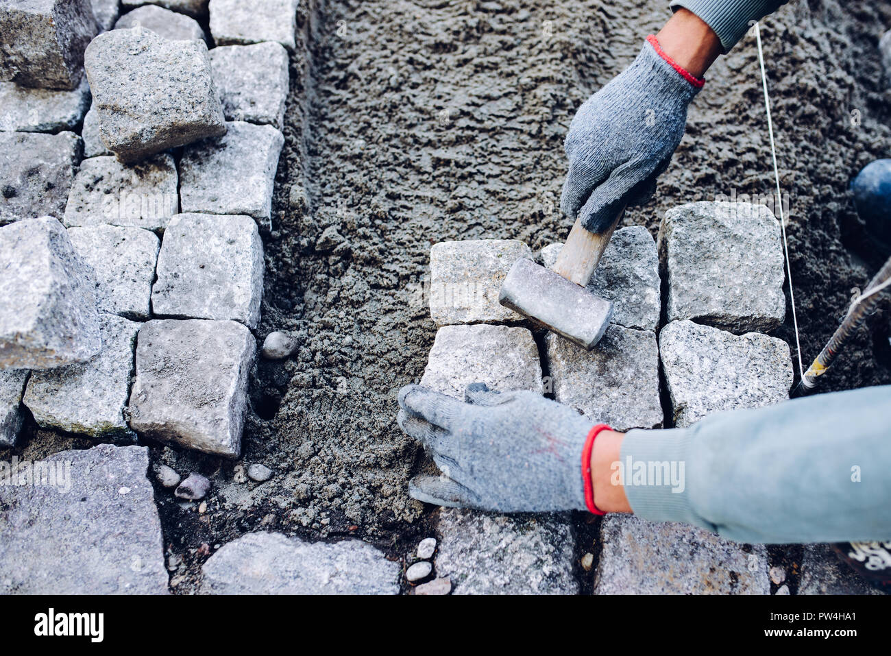industrial worker installing pavement rocks, cobblestone blocks on road ...