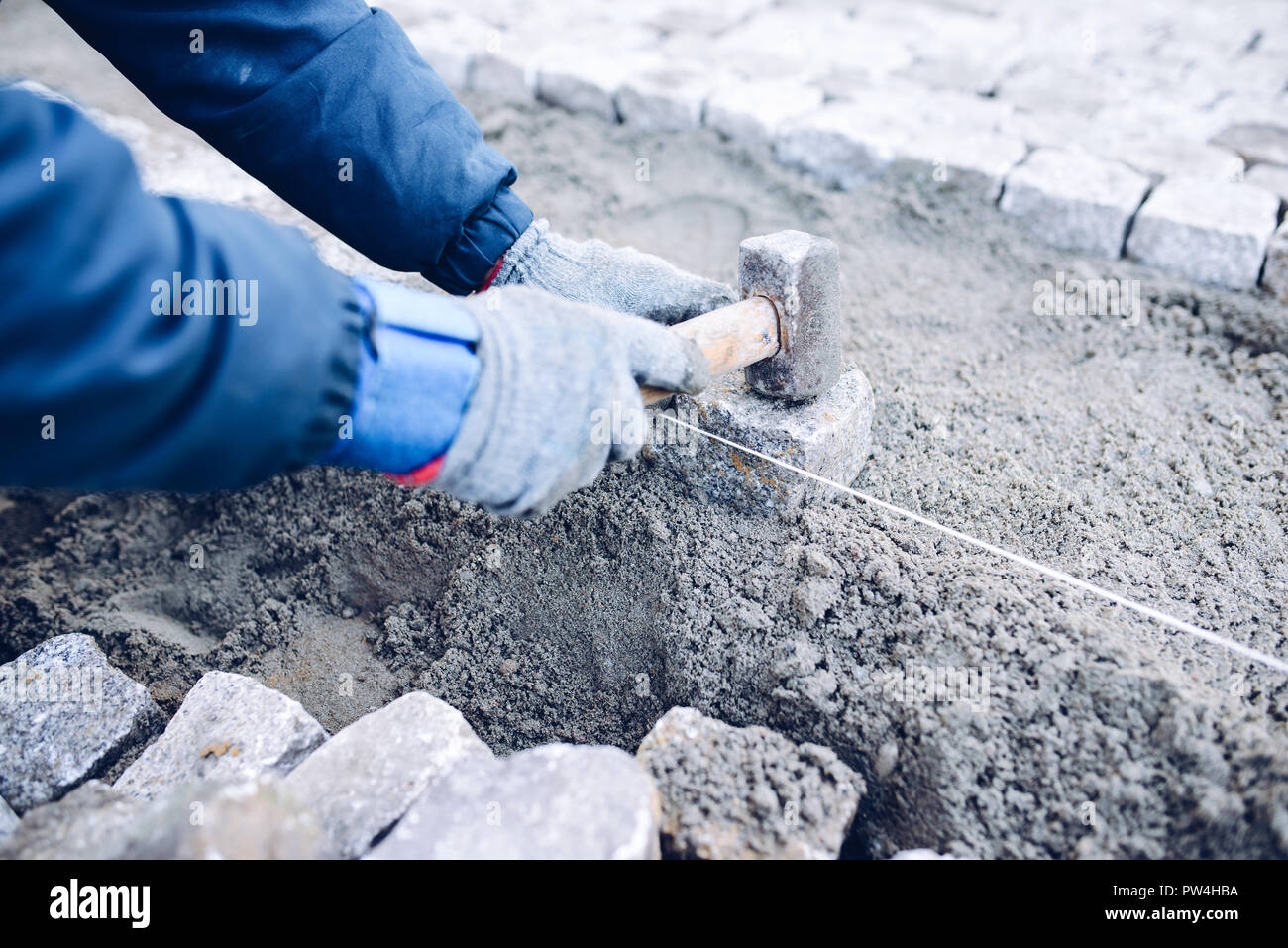 construction worker placing stone tiles for pavement, terrace. Worker ...
