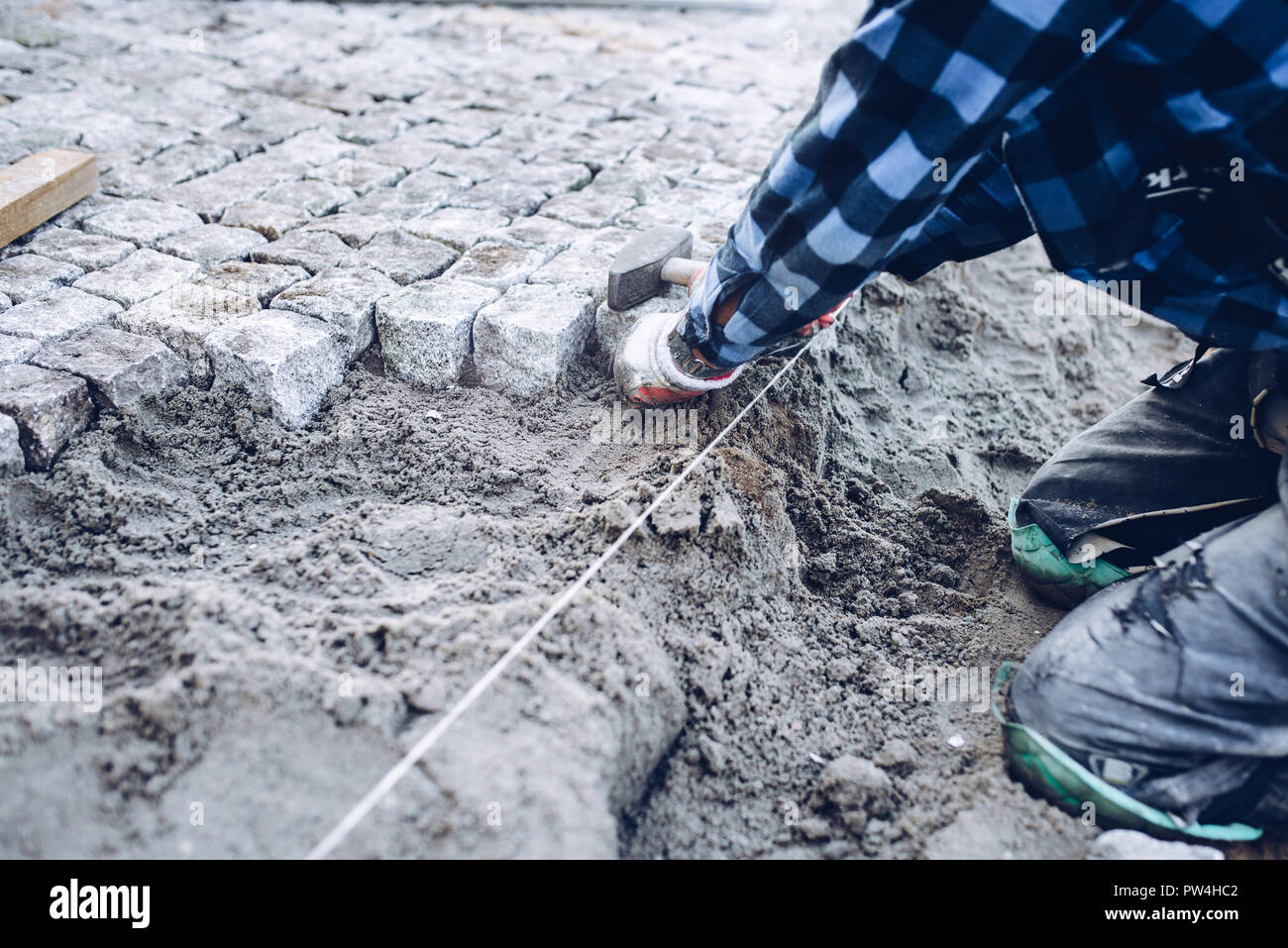 industrial worker installing pavement rocks, cobblestone blocks on road ...