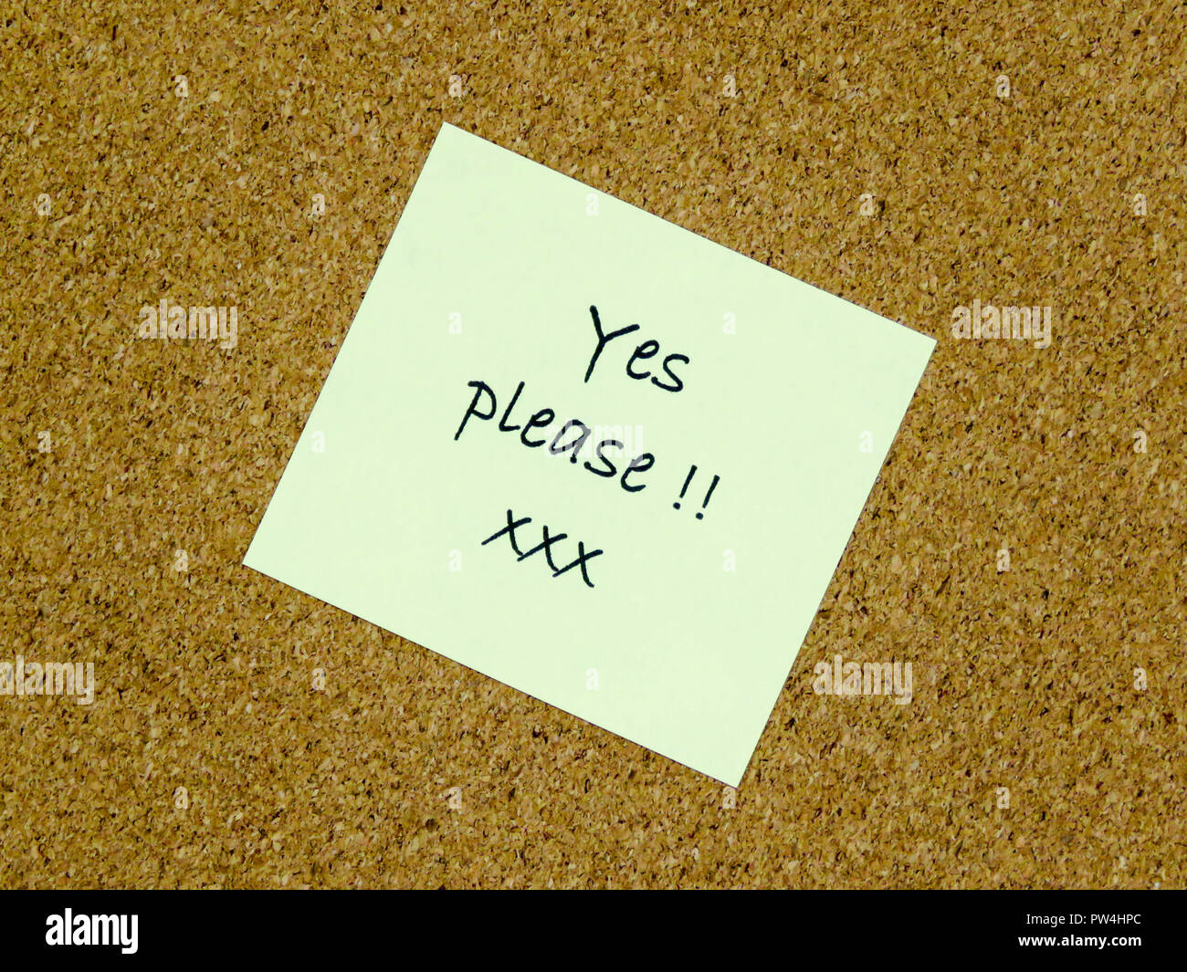 A yellow sticky note with yes please written on it on a cork board ...