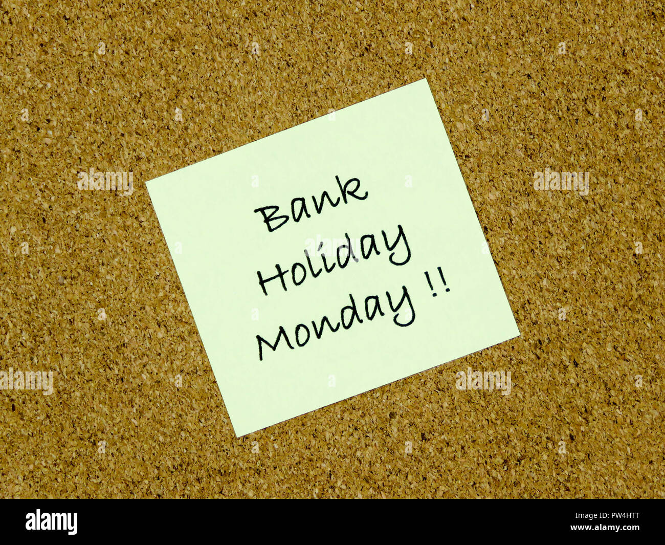 A yellow sticky note with bank holiday Monday written on it on a cork ...