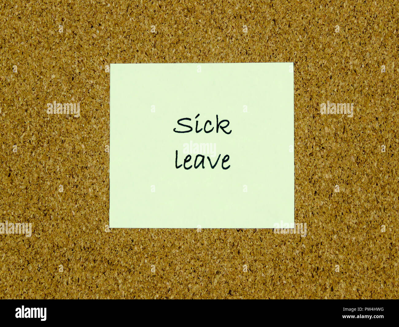A yellow sticky note with sick leave written on it on a cork board ...