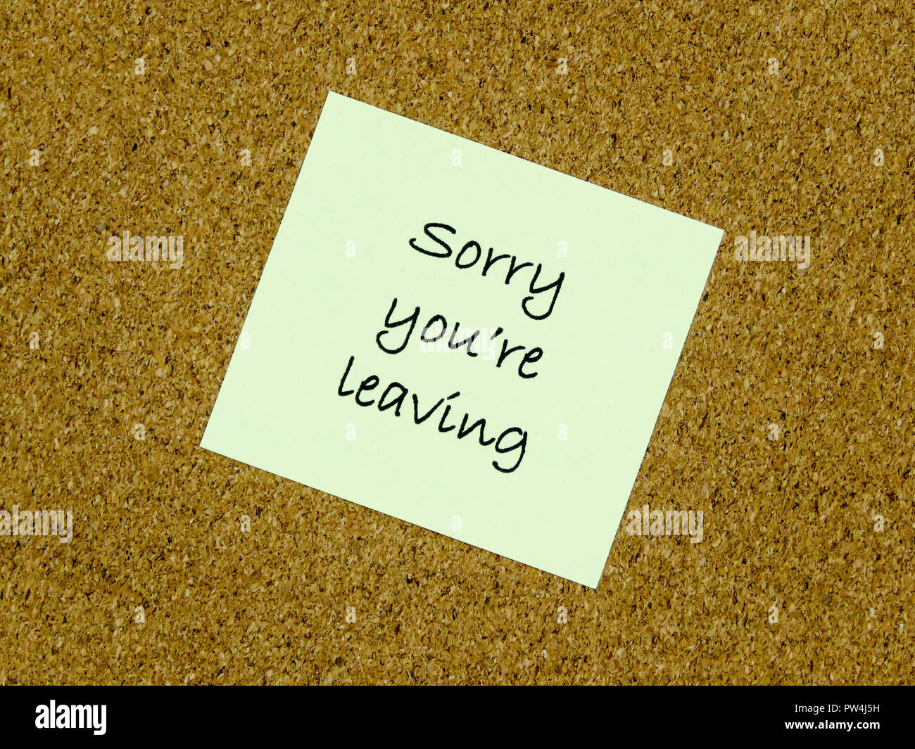 A yellow sticky note with sorry you're leaving written on it on a cork ...