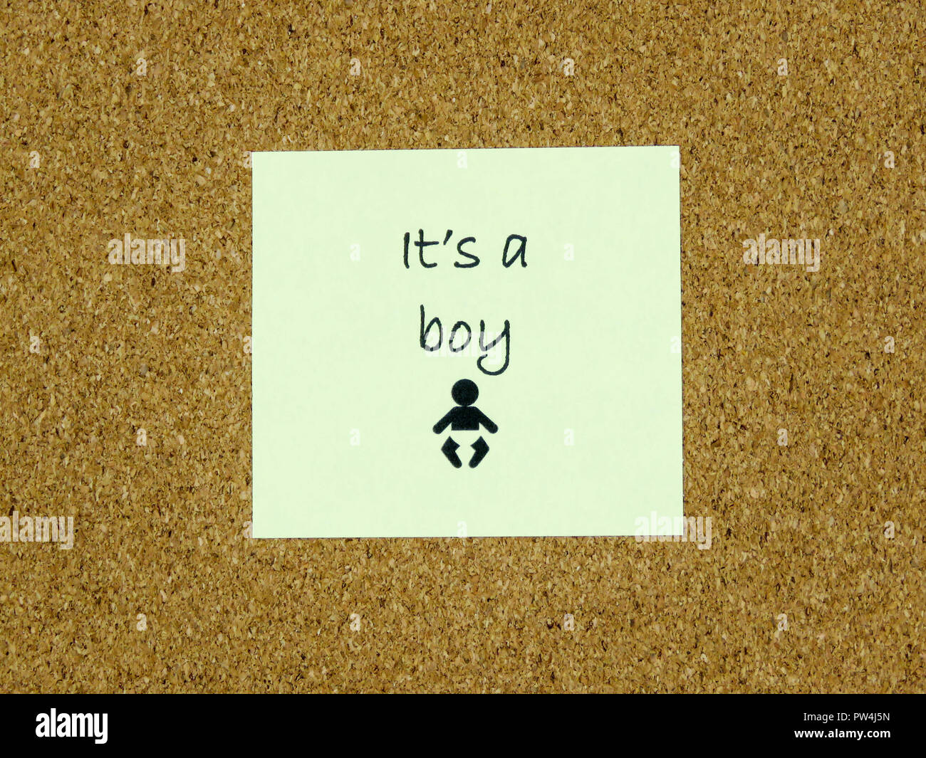A yellow sticky note with its a boy written on it on a cork board ...
